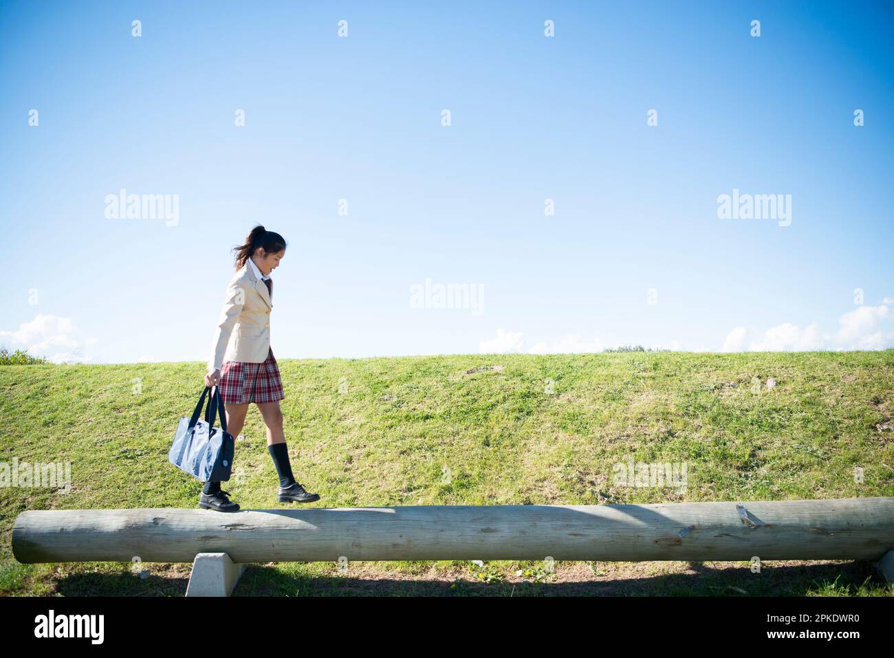 Schoolgirl in school uniform walking on a tree Stock Photo - Alamy