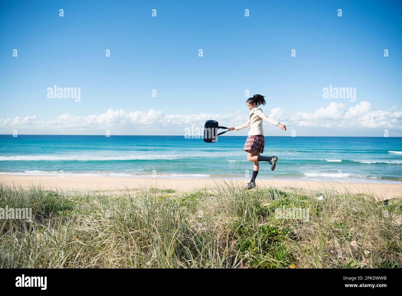 Schoolgirl in school uniform jumping in the sea Stock Photo - Alamy