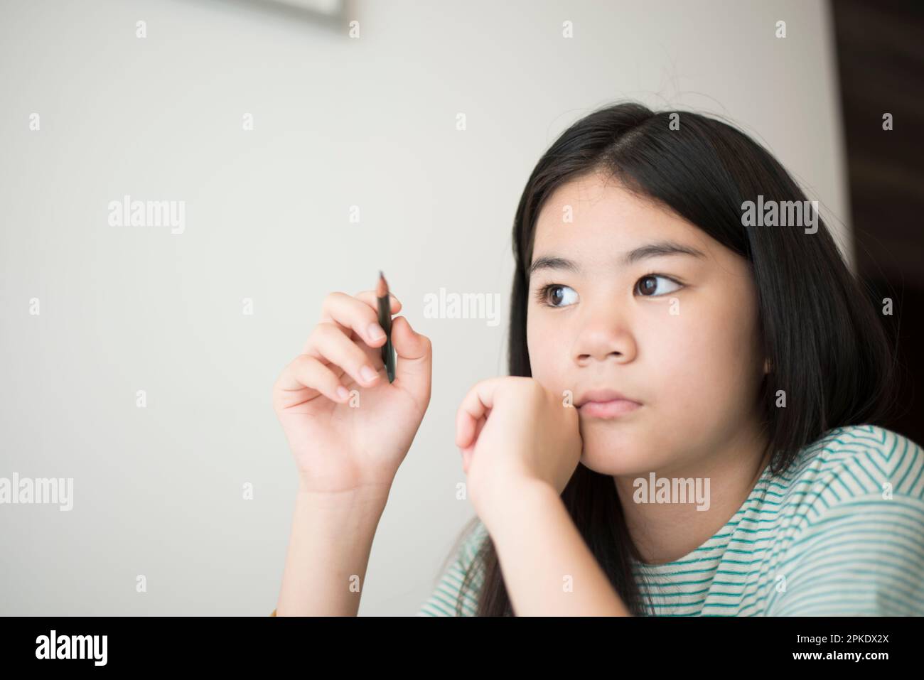 Girl thinking with a pencil Stock Photo - Alamy
