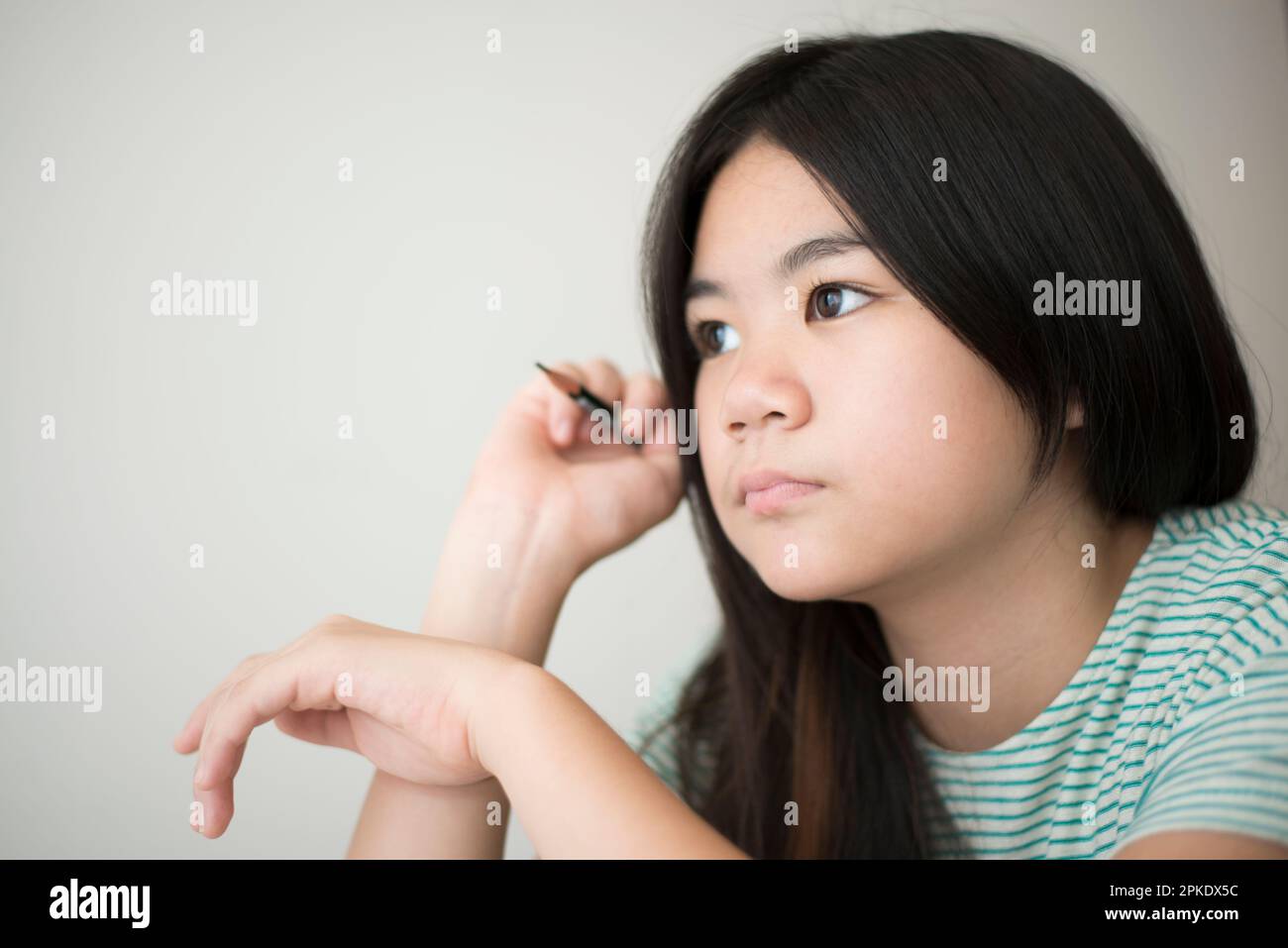 Girl thinking with pencil Stock Photo - Alamy