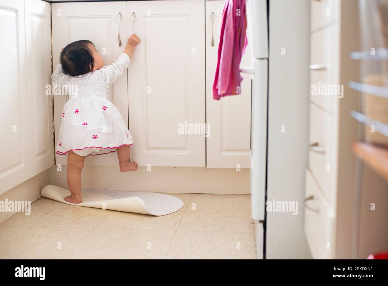 Baby playing in kitchen Stock Photo - Alamy