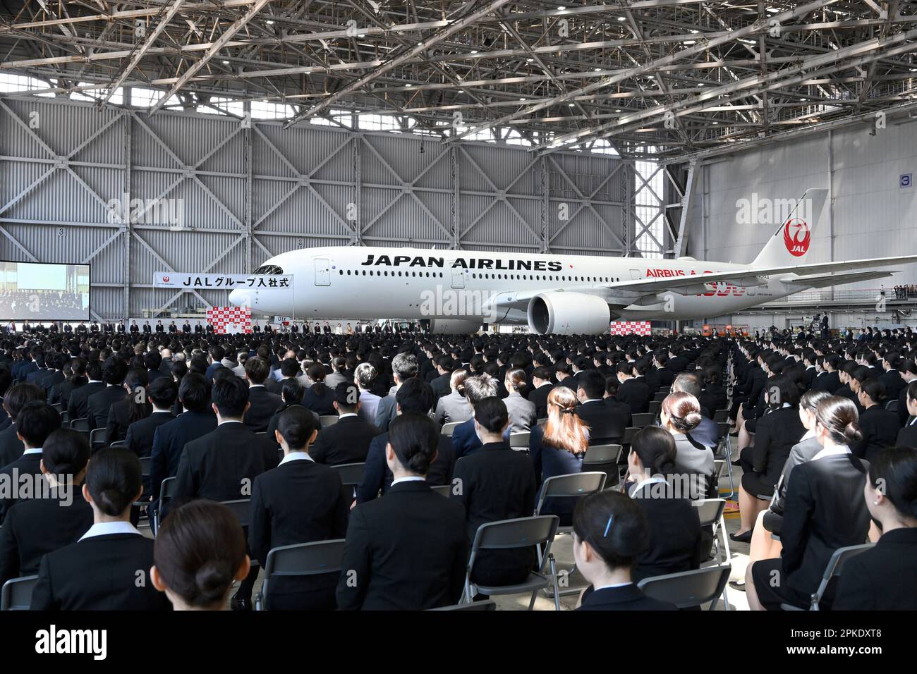 New employees attend the JAL Group entrance ceremony held in a hangar ...