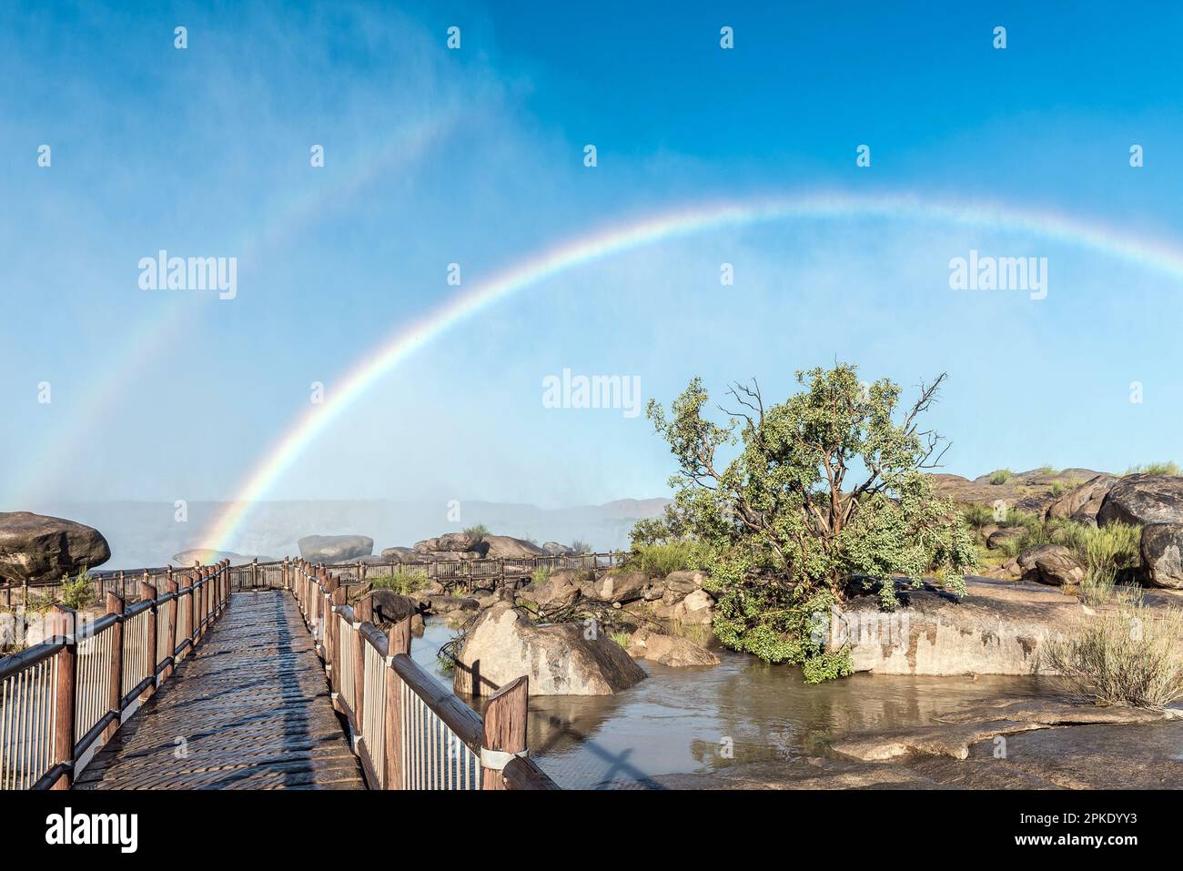 A rainbow is visible over a boardwalk at the Augrabies waterfalls in ...