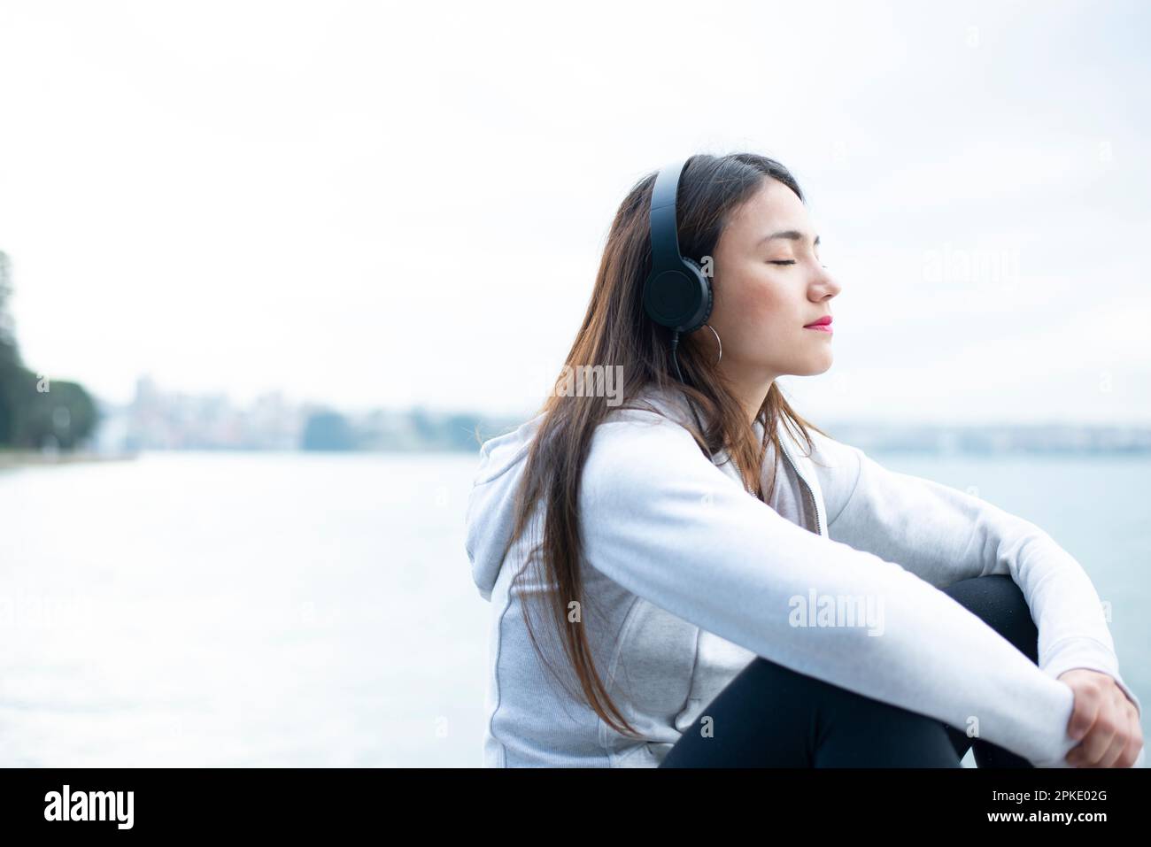 Woman listening to music with her eyes closed at the water's edge Stock ...