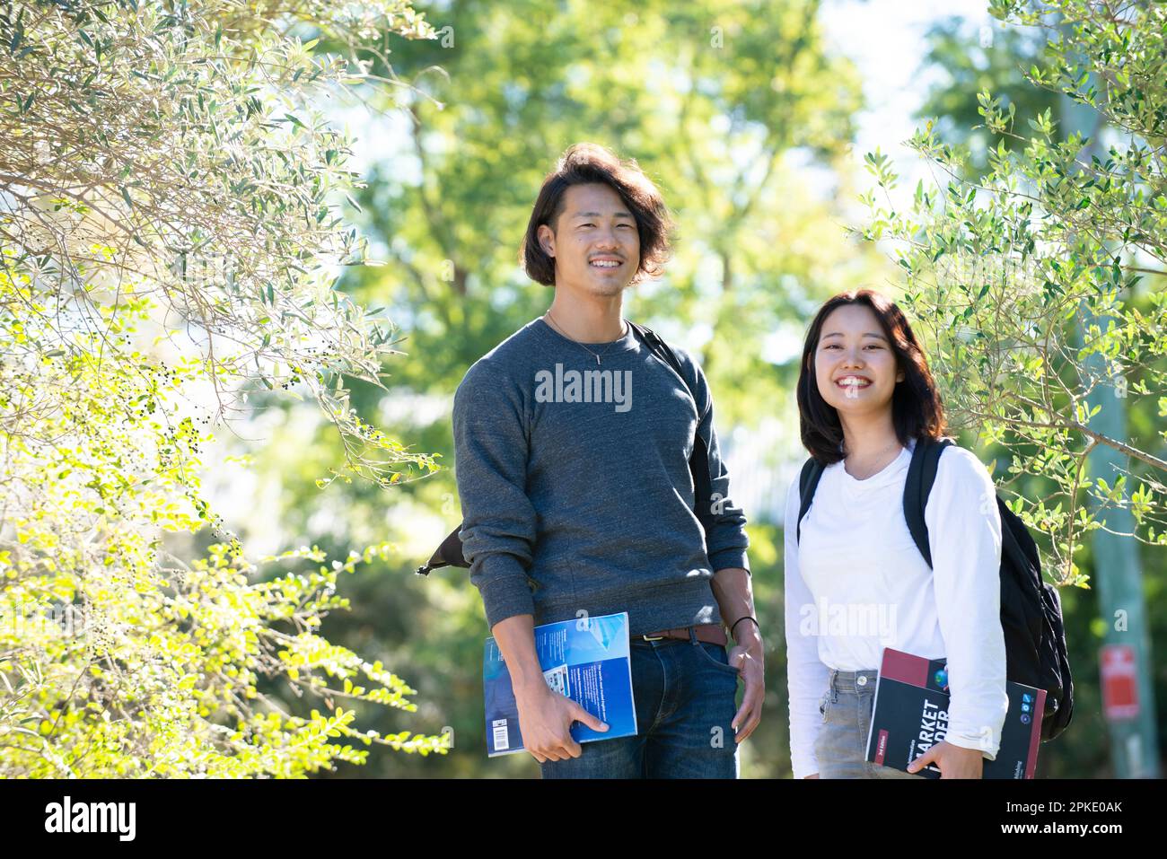 Male and female students standing in green Stock Photo - Alamy
