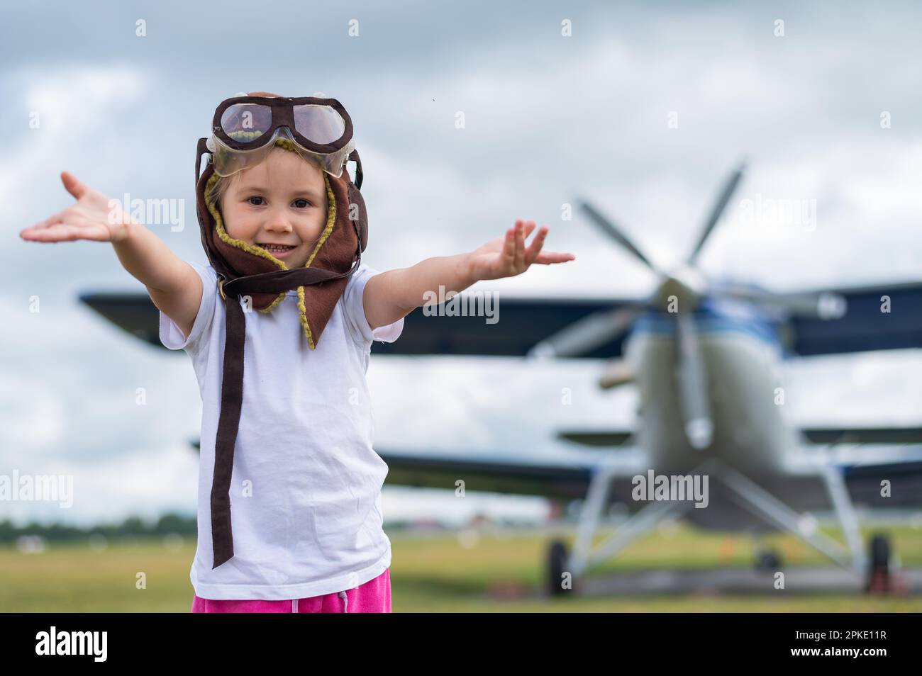 A cute little girl dressed in a cap and glasses of a pilot on the ...