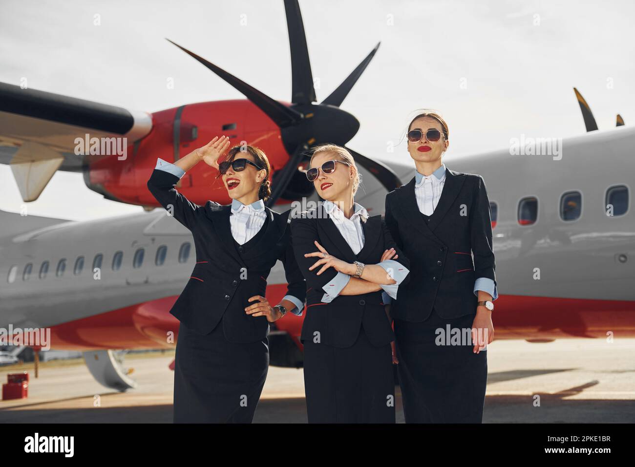 Three stewardesses. Crew of airport and plane workers in formal clothes ...