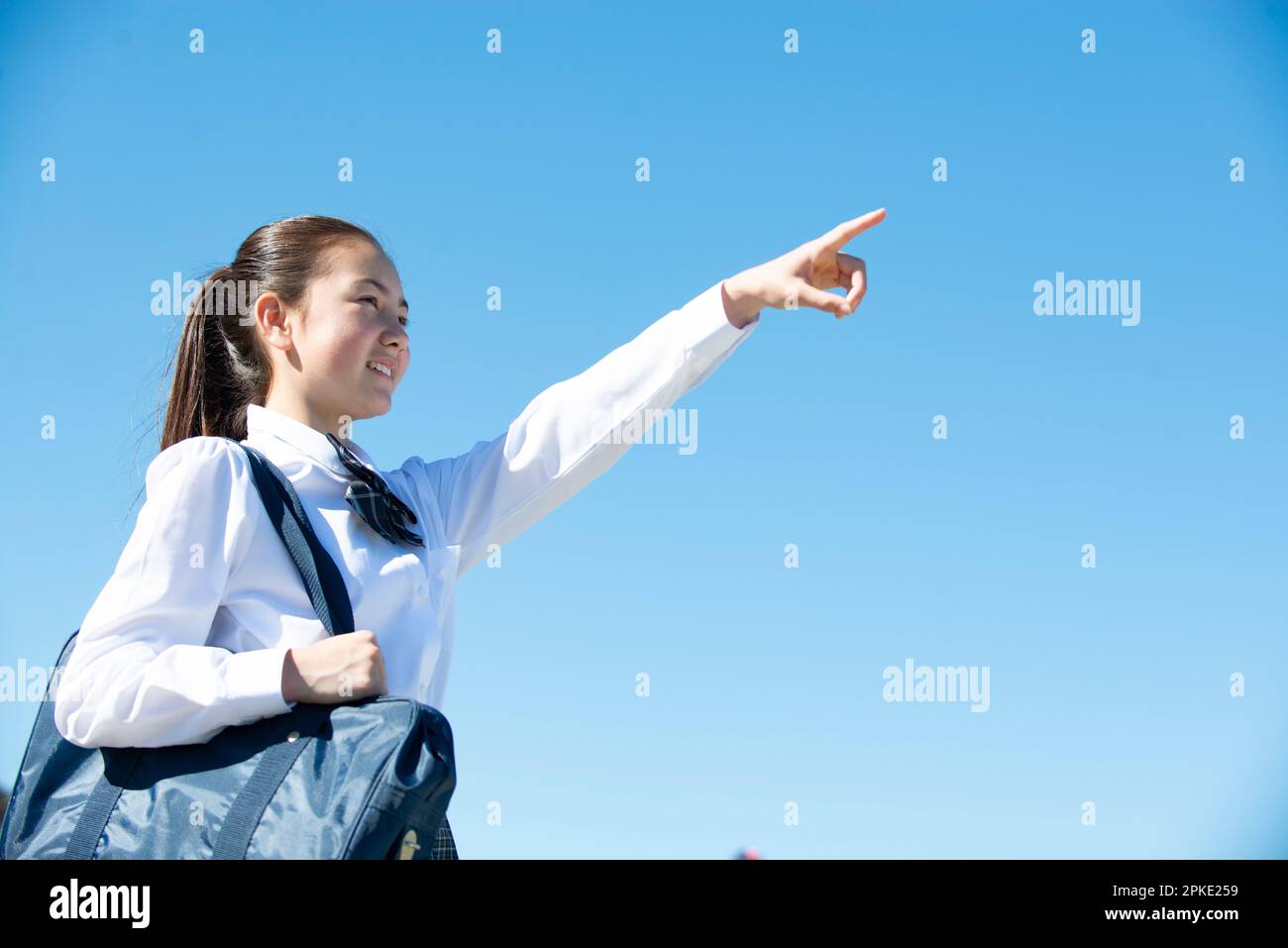 Female student in school uniform pointing into the distance Stock Photo ...