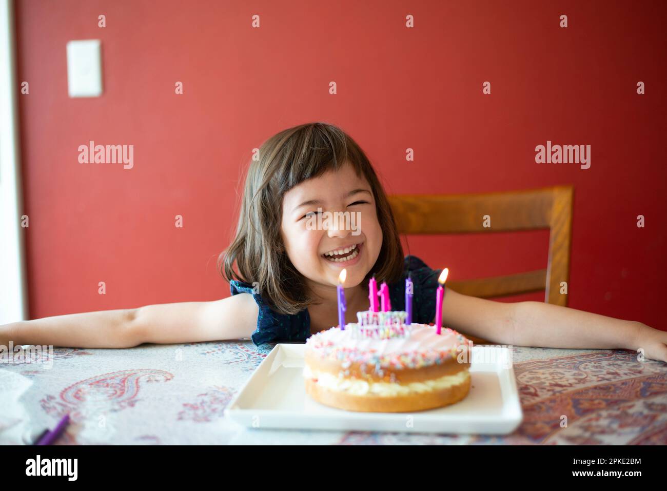 Girl laughing in front of birthday cake Stock Photo - Alamy