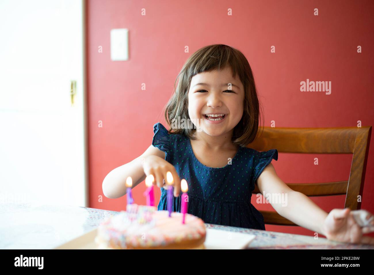 Girl laughing in front of birthday cake Stock Photo - Alamy