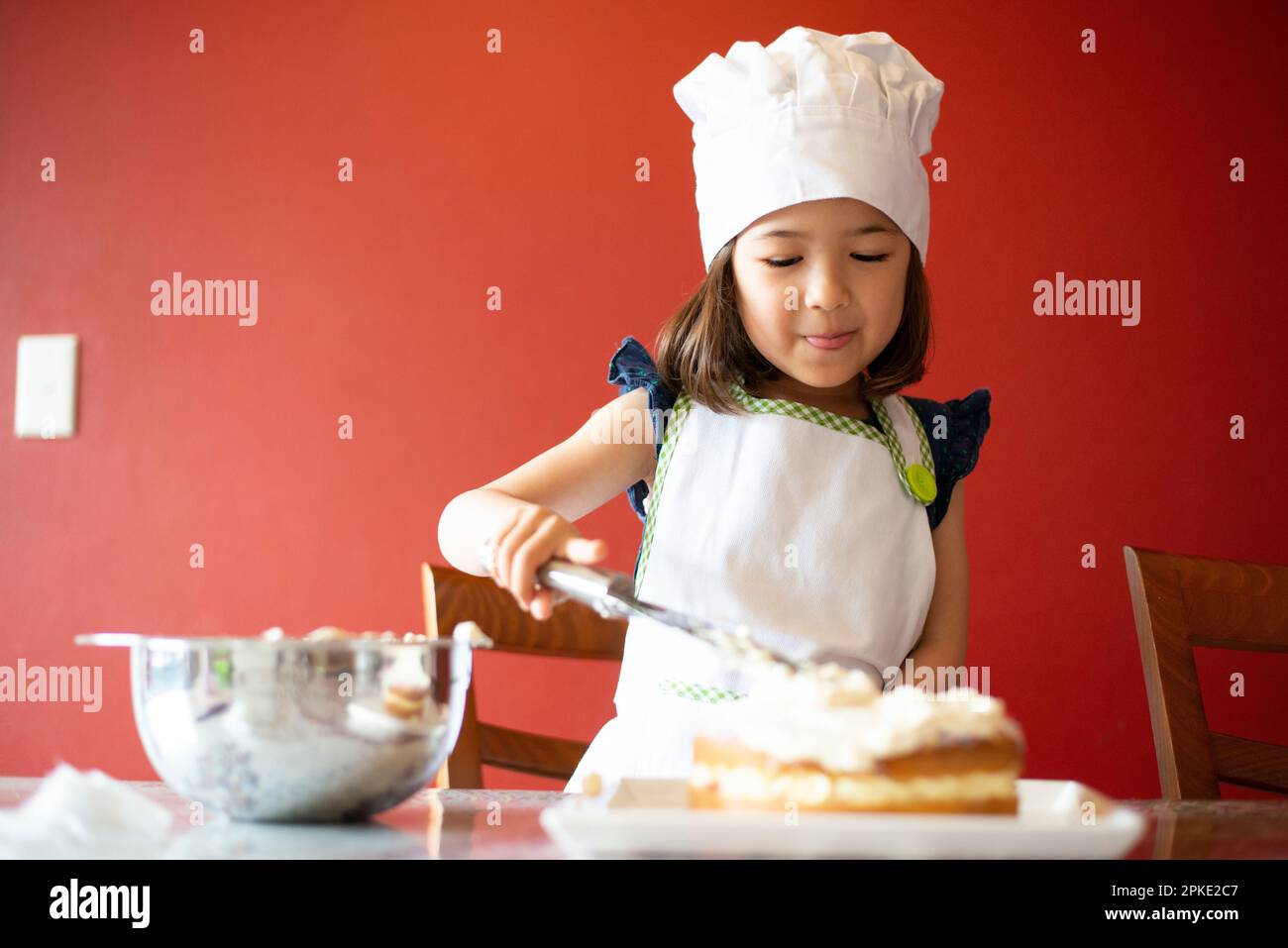 Girl applying cream to cake Stock Photo - Alamy