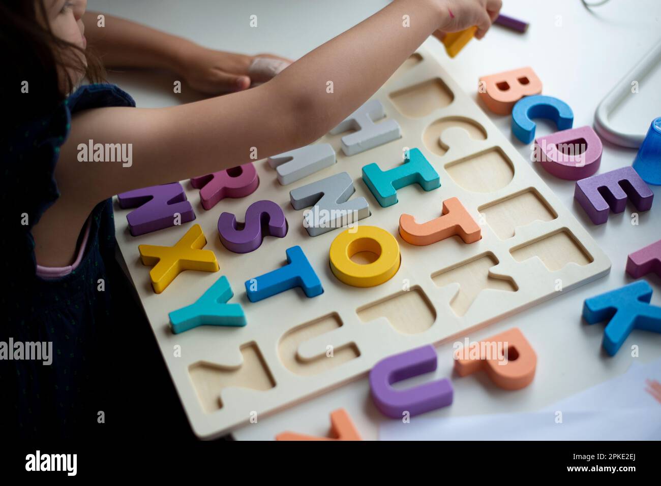 Child's hand playing with wooden alphabet toy Stock Photo - Alamy
