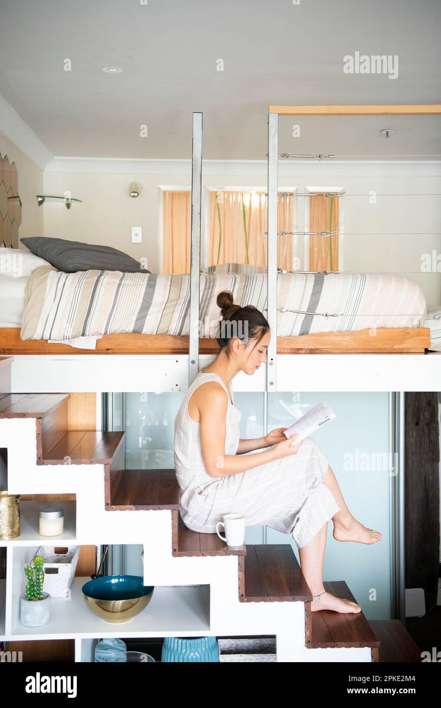 Fashionable young woman sitting on stairs reading a book hi-res stock ...