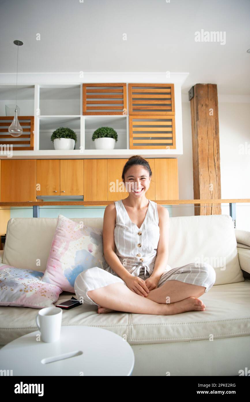 Woman sitting cross-legged on the sofa Stock Photo - Alamy