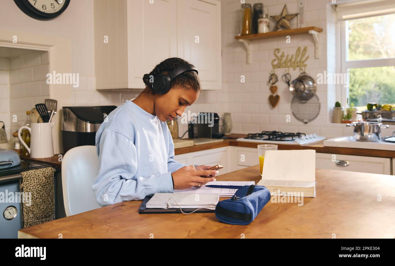 Teen girl doing homework and using phone texting Stock Photo - Alamy