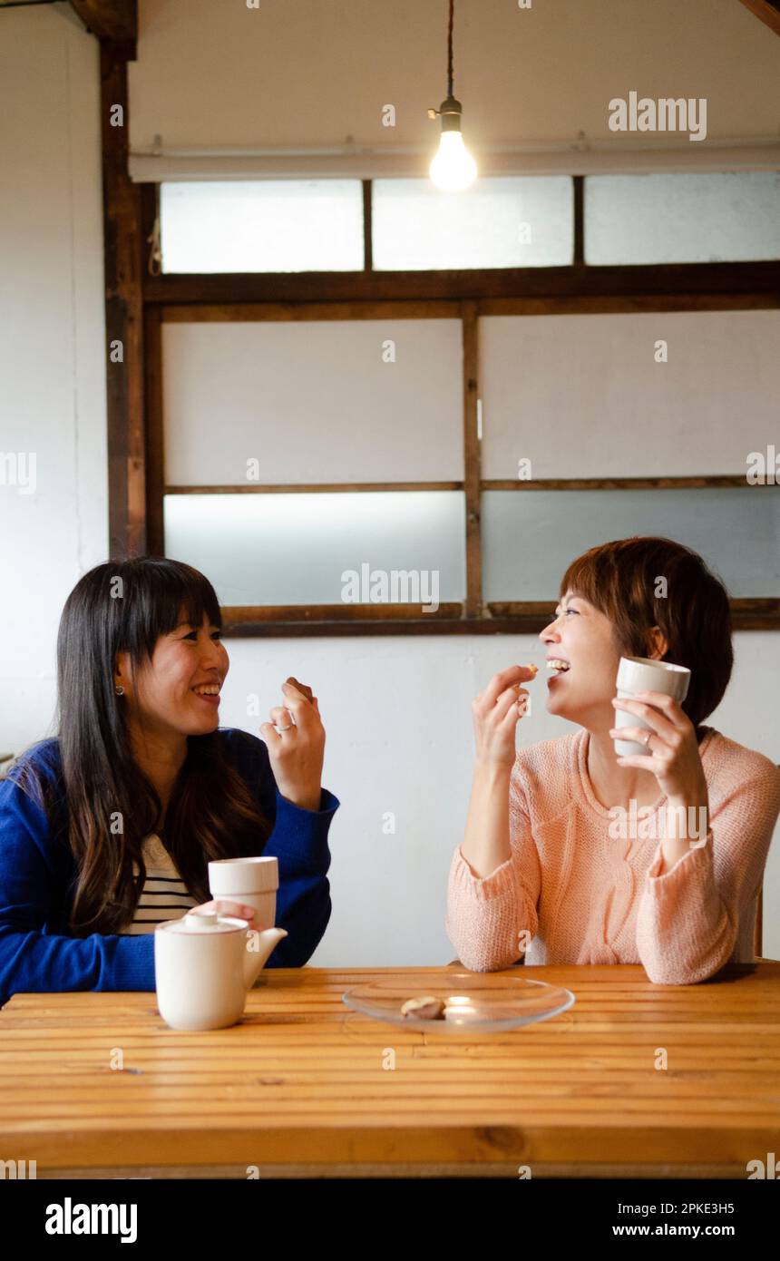 Two women laughing while drinking tea Stock Photo - Alamy