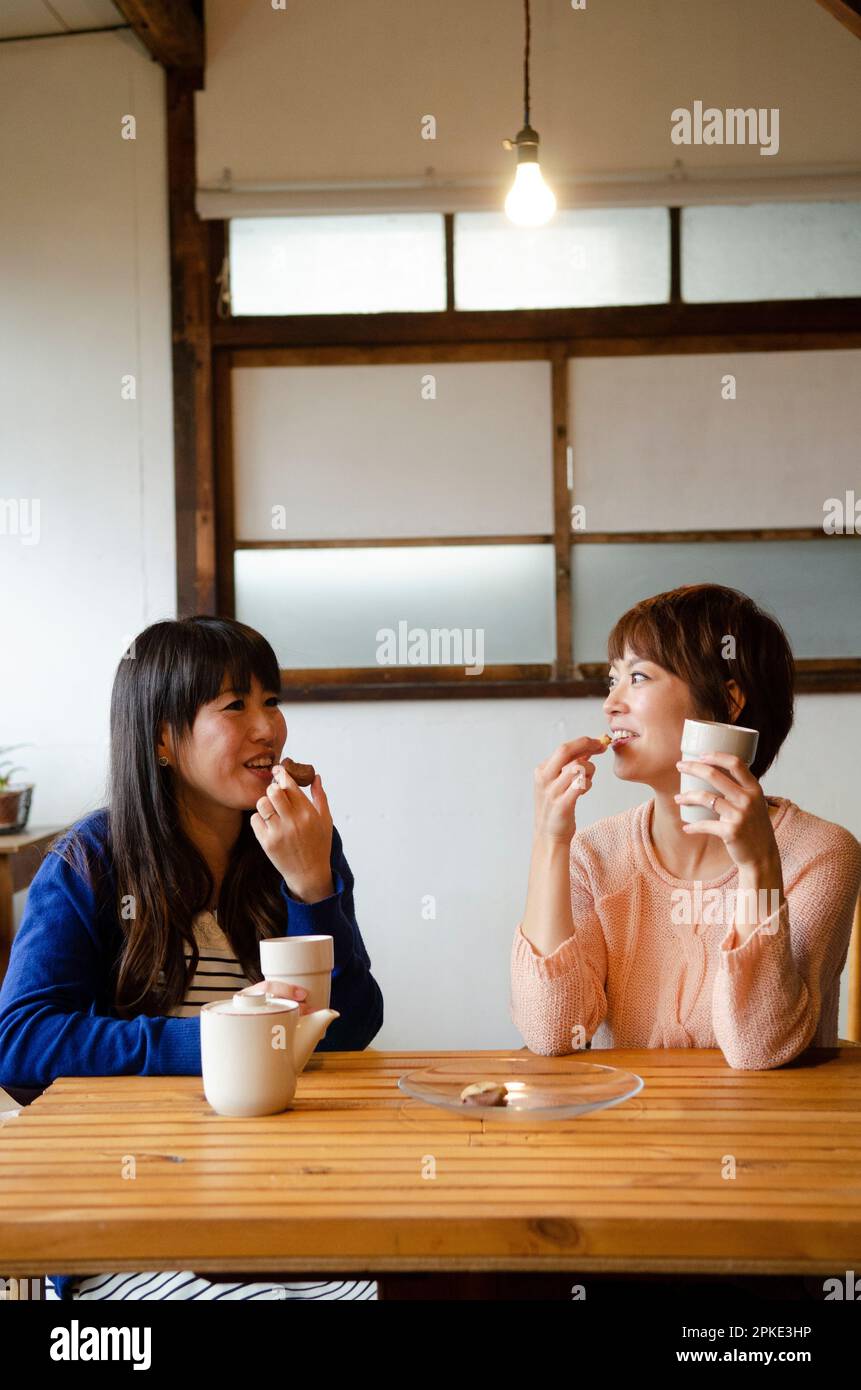 Two women laughing while drinking tea Stock Photo - Alamy