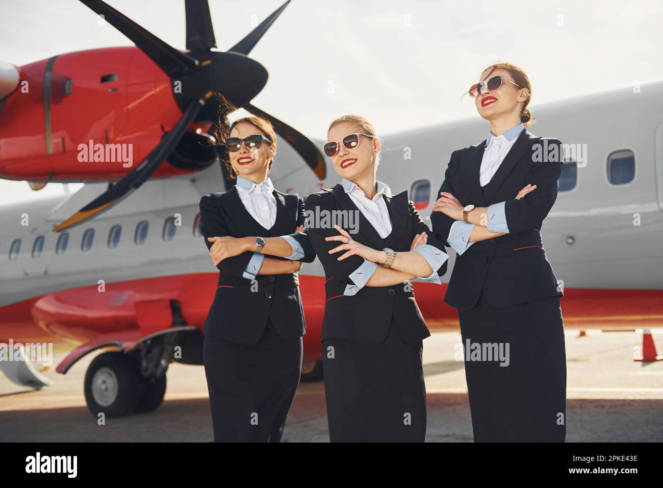 Three stewardesses. Crew of airport and plane workers in formal clothes ...