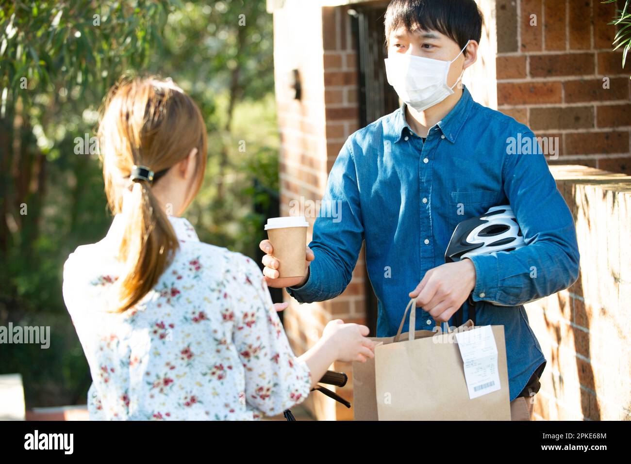Man and woman handing over food delivery items Stock Photo - Alamy