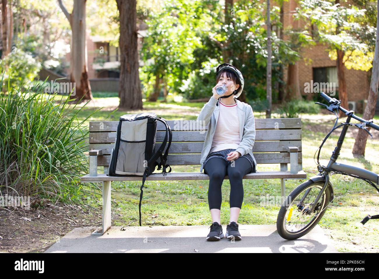 Food delivery woman taking a break on a bench Stock Photo - Alamy