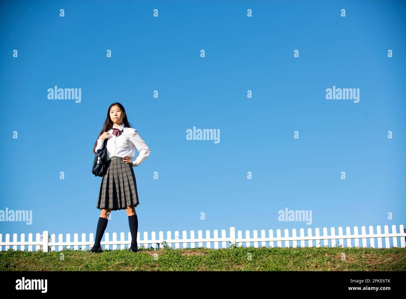 Female student in school uniform standing under blue sky Stock Photo ...