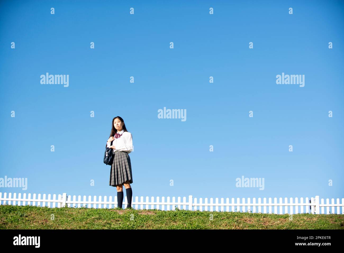 Female student in school uniform standing under blue sky Stock Photo ...