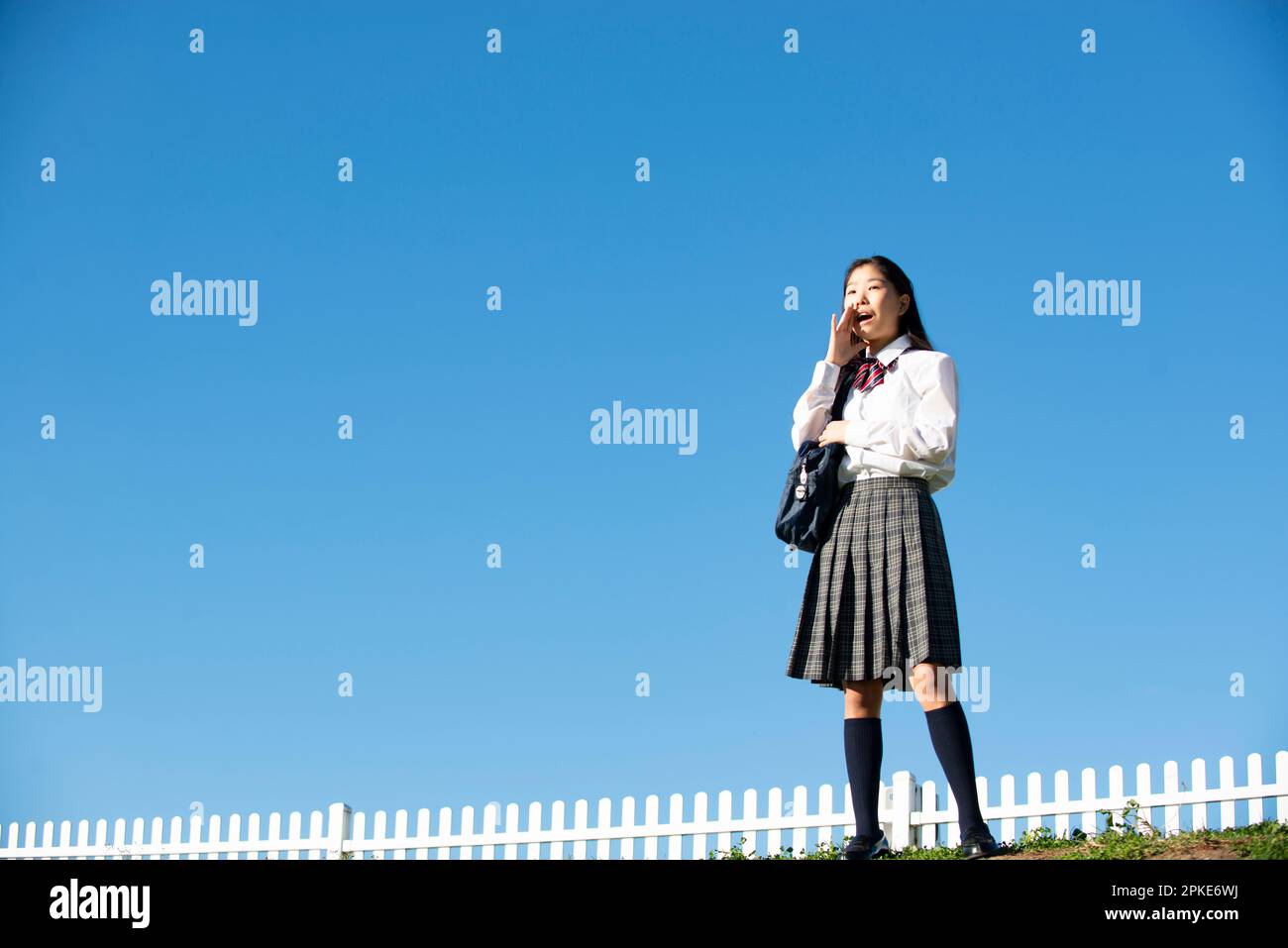 Female student in school uniform holding her hand over her mouth and ...