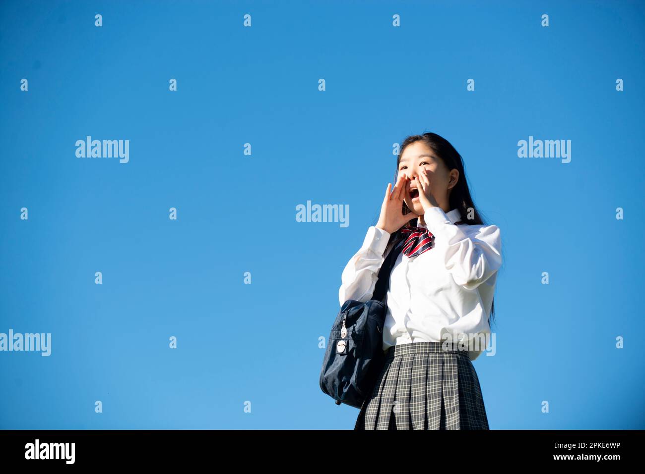 Female student in school uniform holding her hand over her mouth and ...
