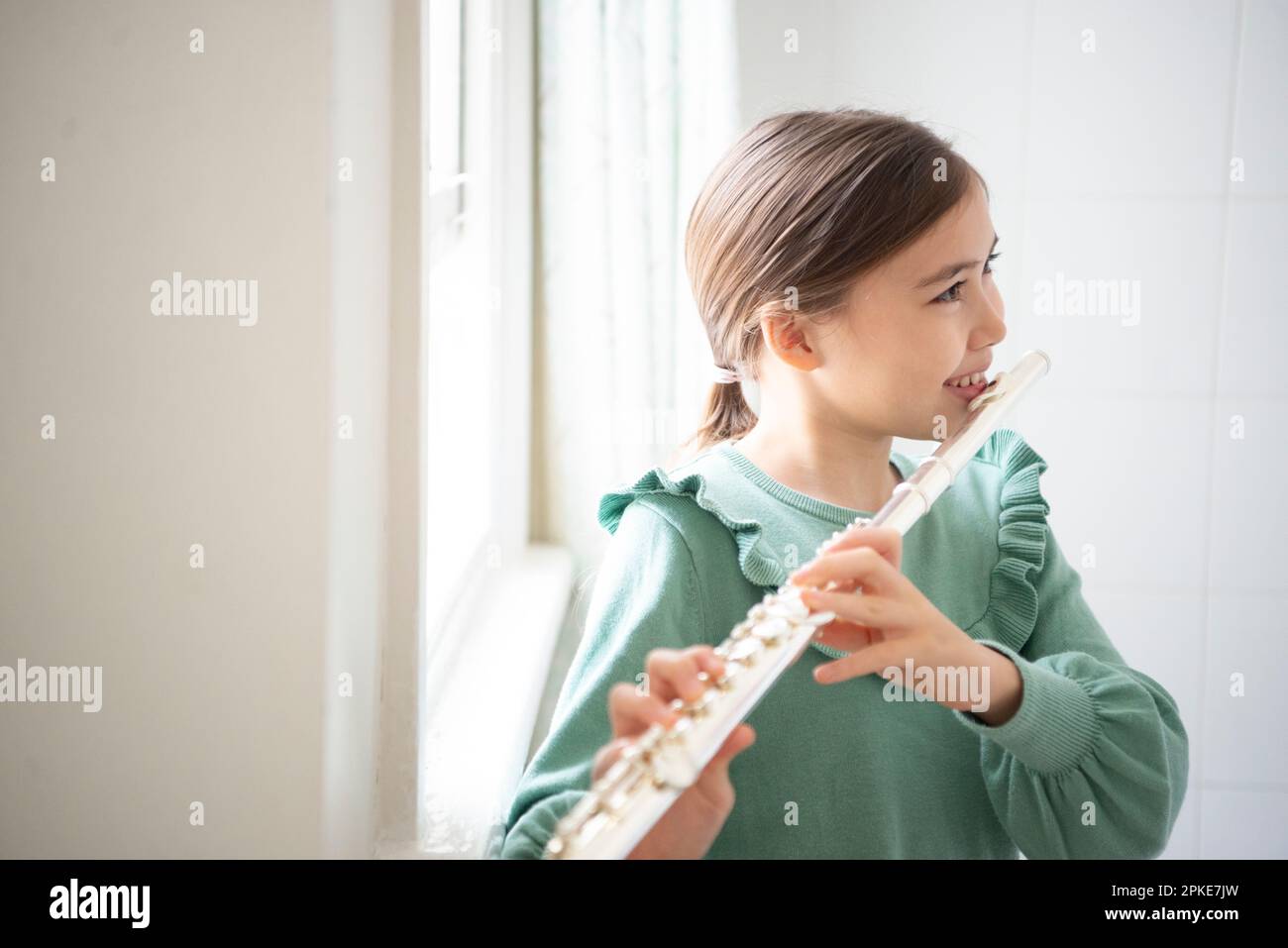 Girl playing flute by the window Stock Photo - Alamy