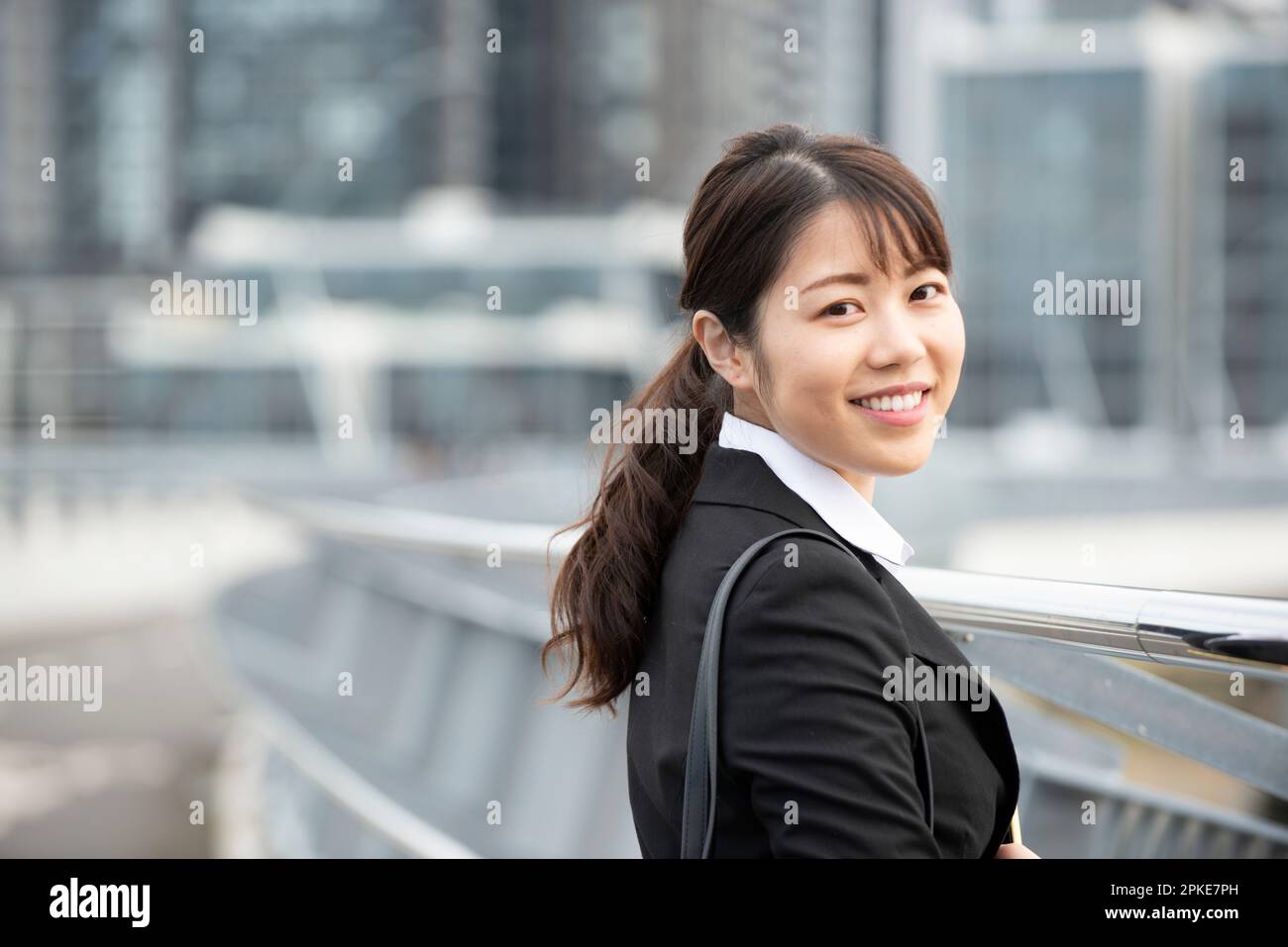 Woman in suit looking back and smiling Stock Photo - Alamy