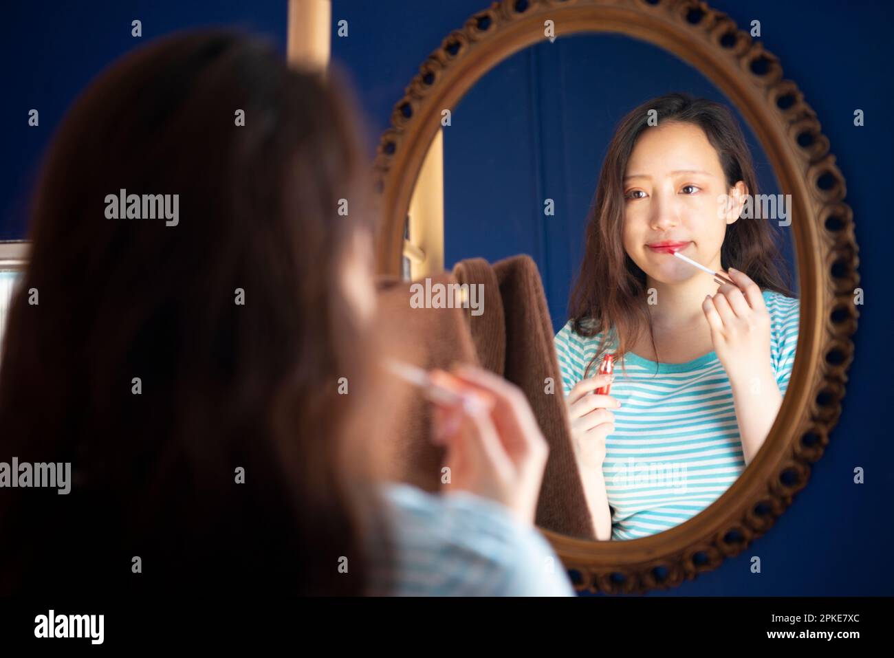 Woman doing her makeup while looking in the mirror Stock Photo - Alamy