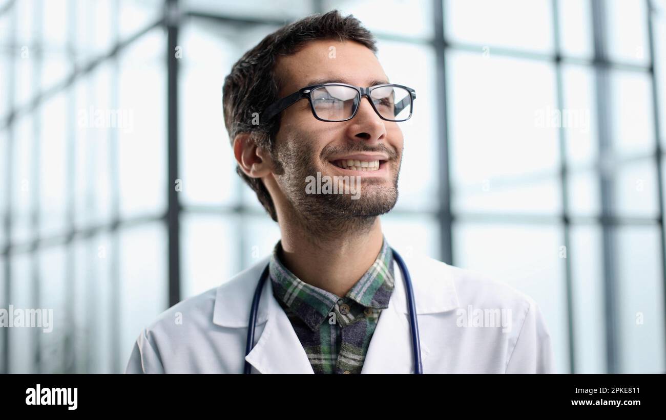 a young doctor stands alone in the studio and poses for the camera ...