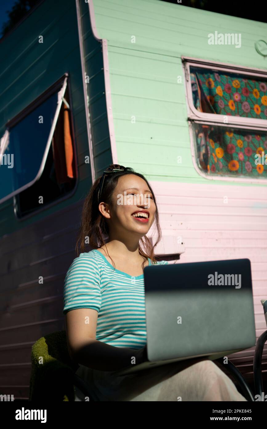 Woman operating a computer in front of a camping trailer Stock Photo ...