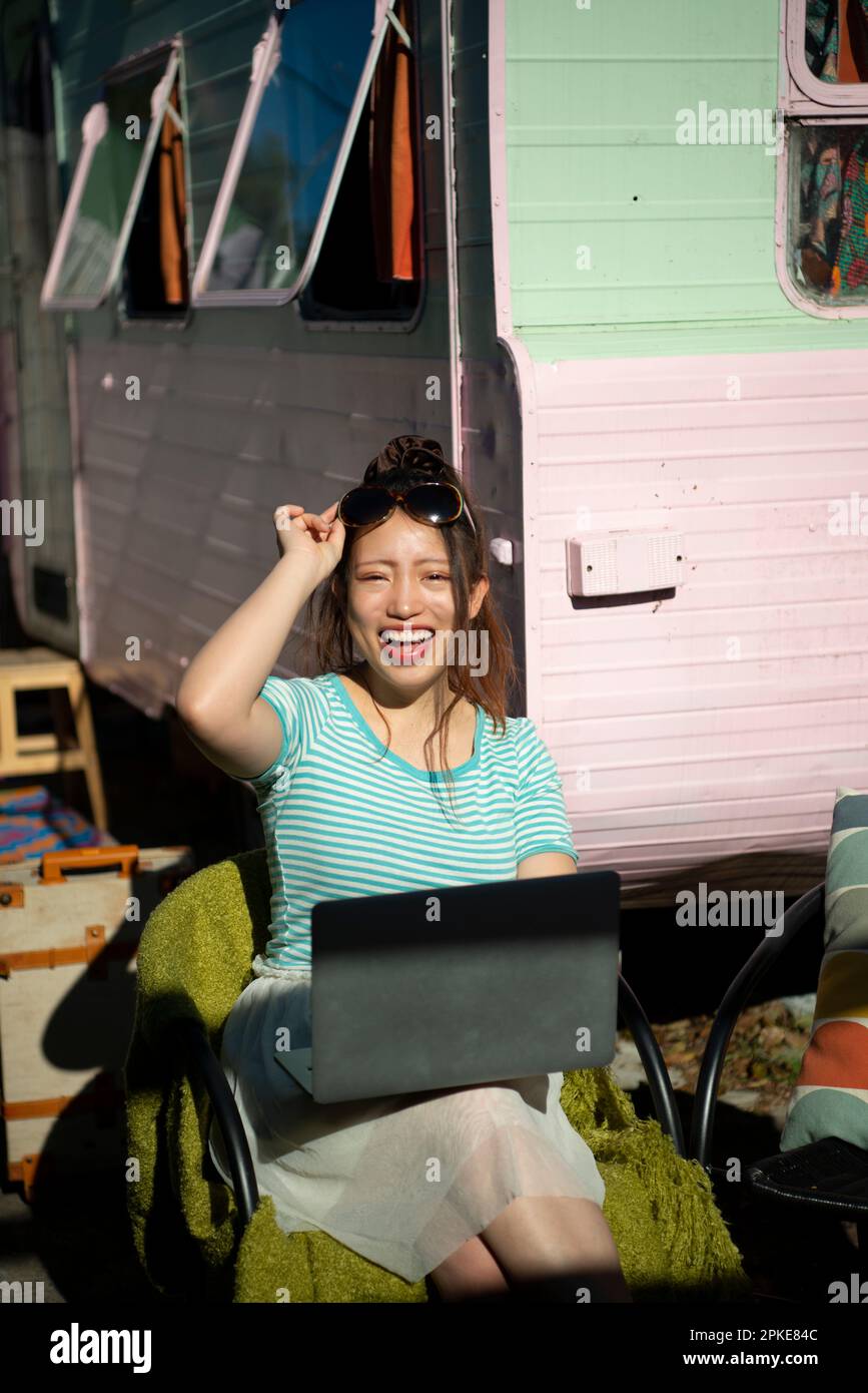Woman operating computer in front of camping trailer Stock Photo - Alamy