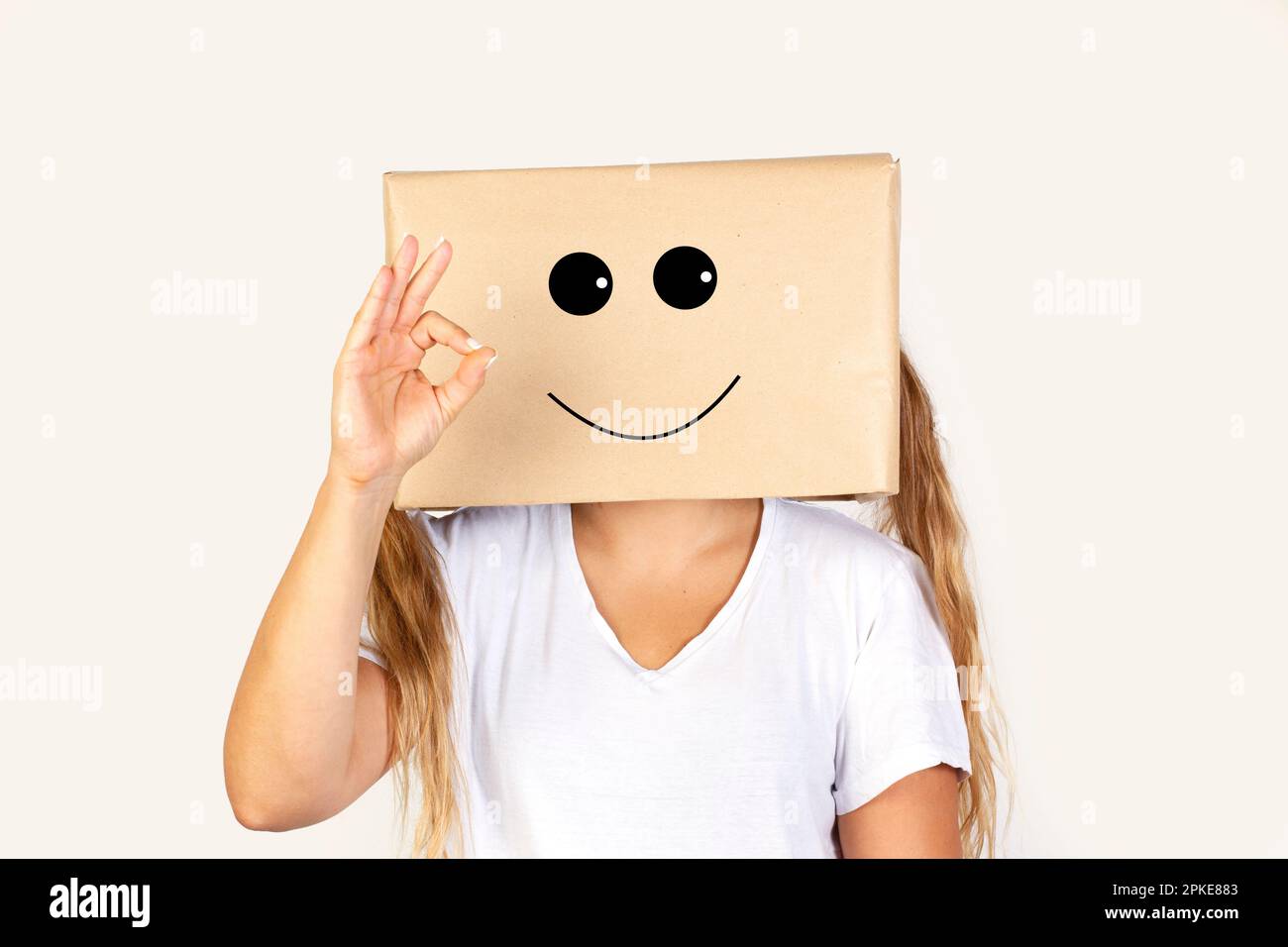 Woman with her head in a box and ok gesture standing on a white ...