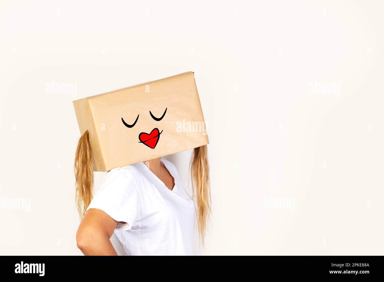 Woman with her head in a box and love gesture standing on a white ...