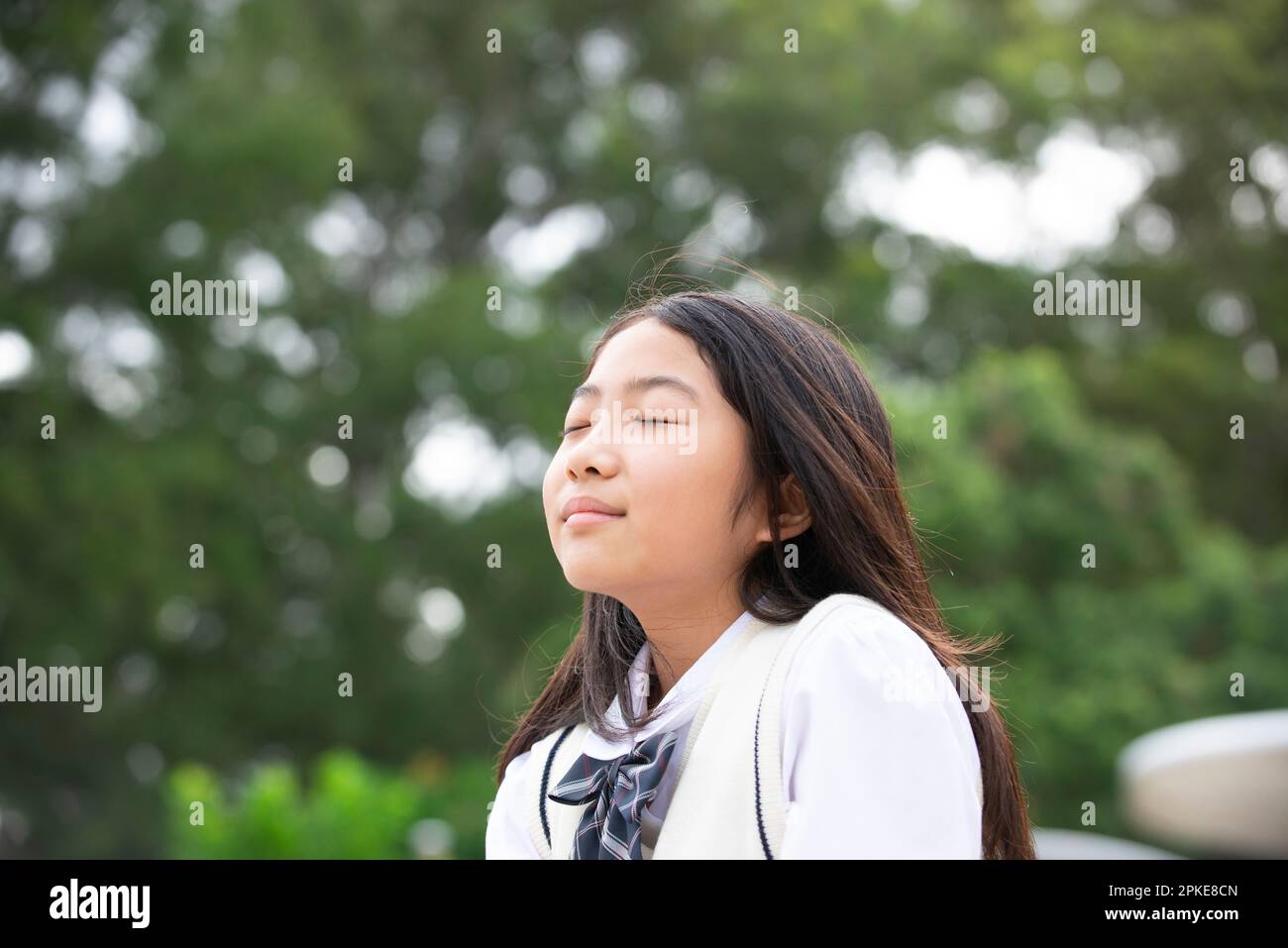 A female student in school uniform taking a deep breath with her eyes ...