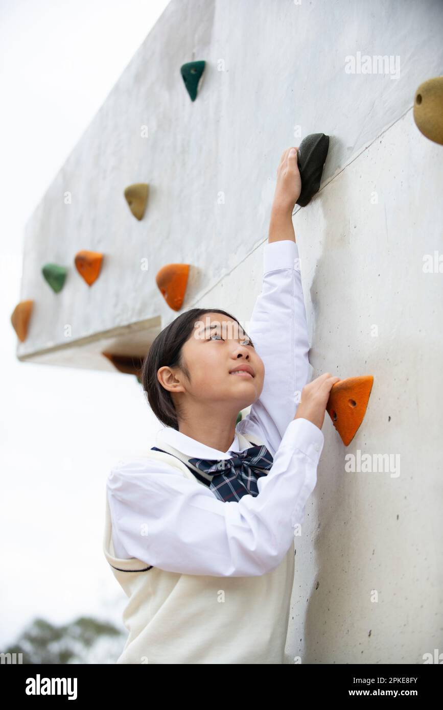 Female student in school uniform climbing the bouldering wall Stock ...