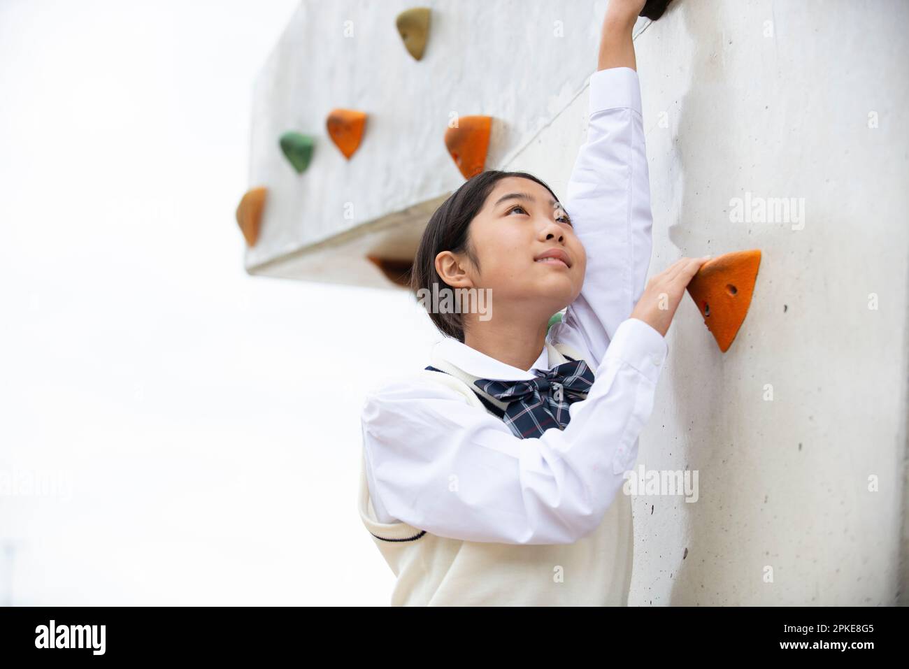Schoolgirl in school uniform climbing the bouldering wall Stock Photo ...