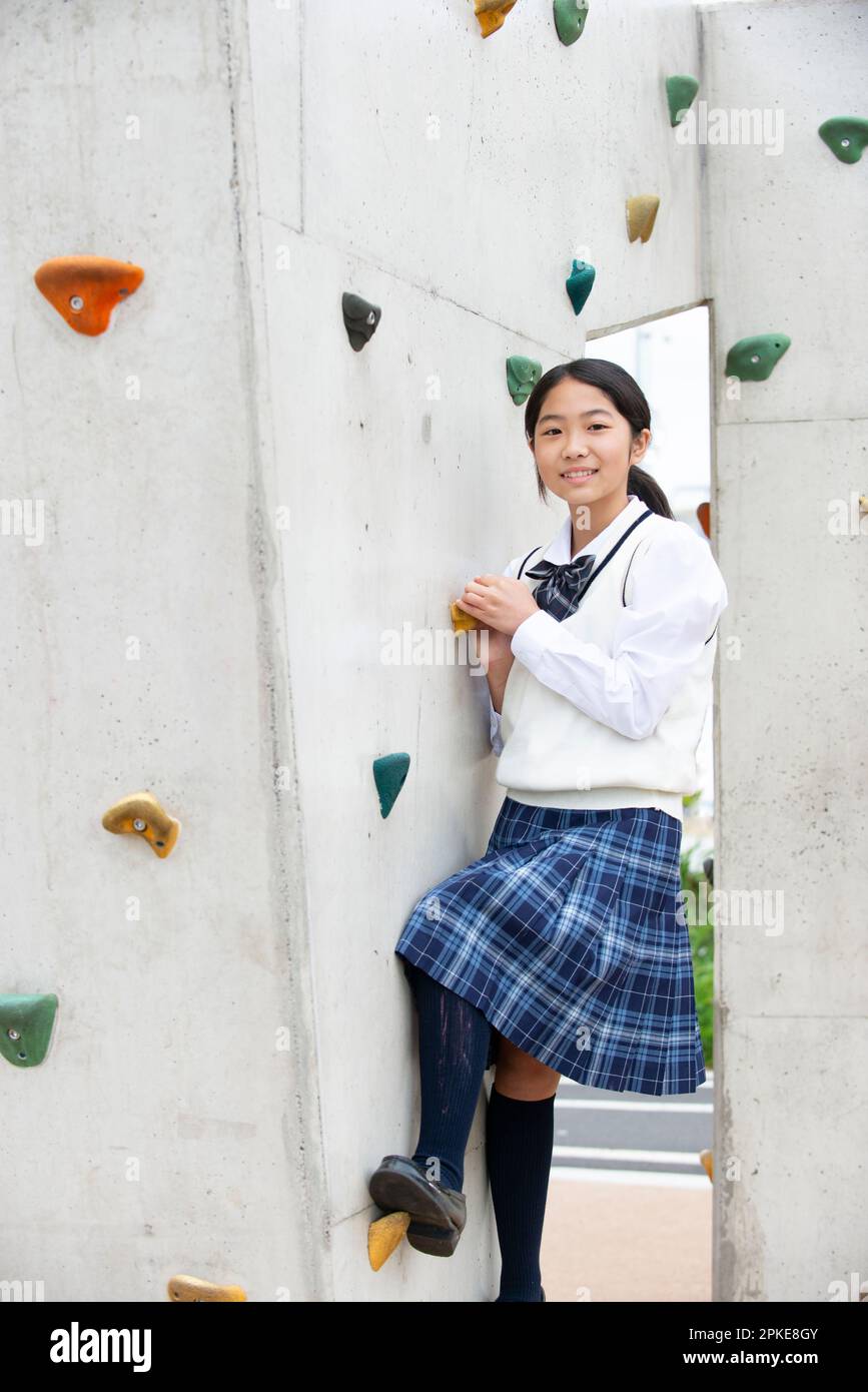 Schoolgirl in school uniform climbing the bouldering wall Stock Photo ...