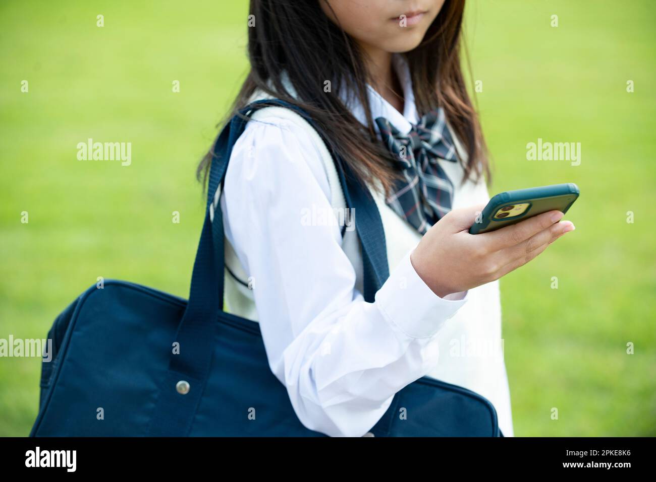Female student in school uniform holding a smartphone Stock Photo - Alamy