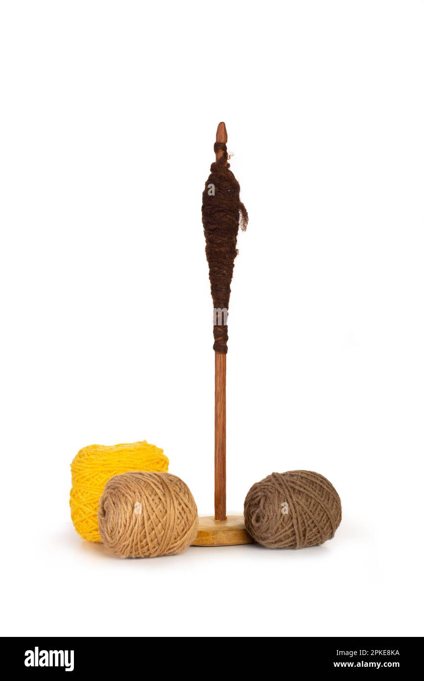Brown and yellow wool spools and a spindle on white background with ...