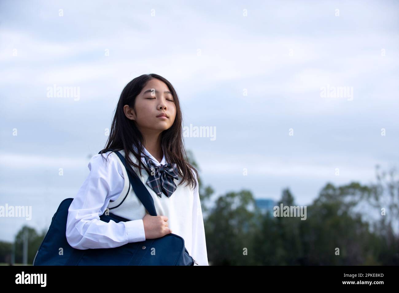 Female student in school uniform with her eyes closed Stock Photo - Alamy