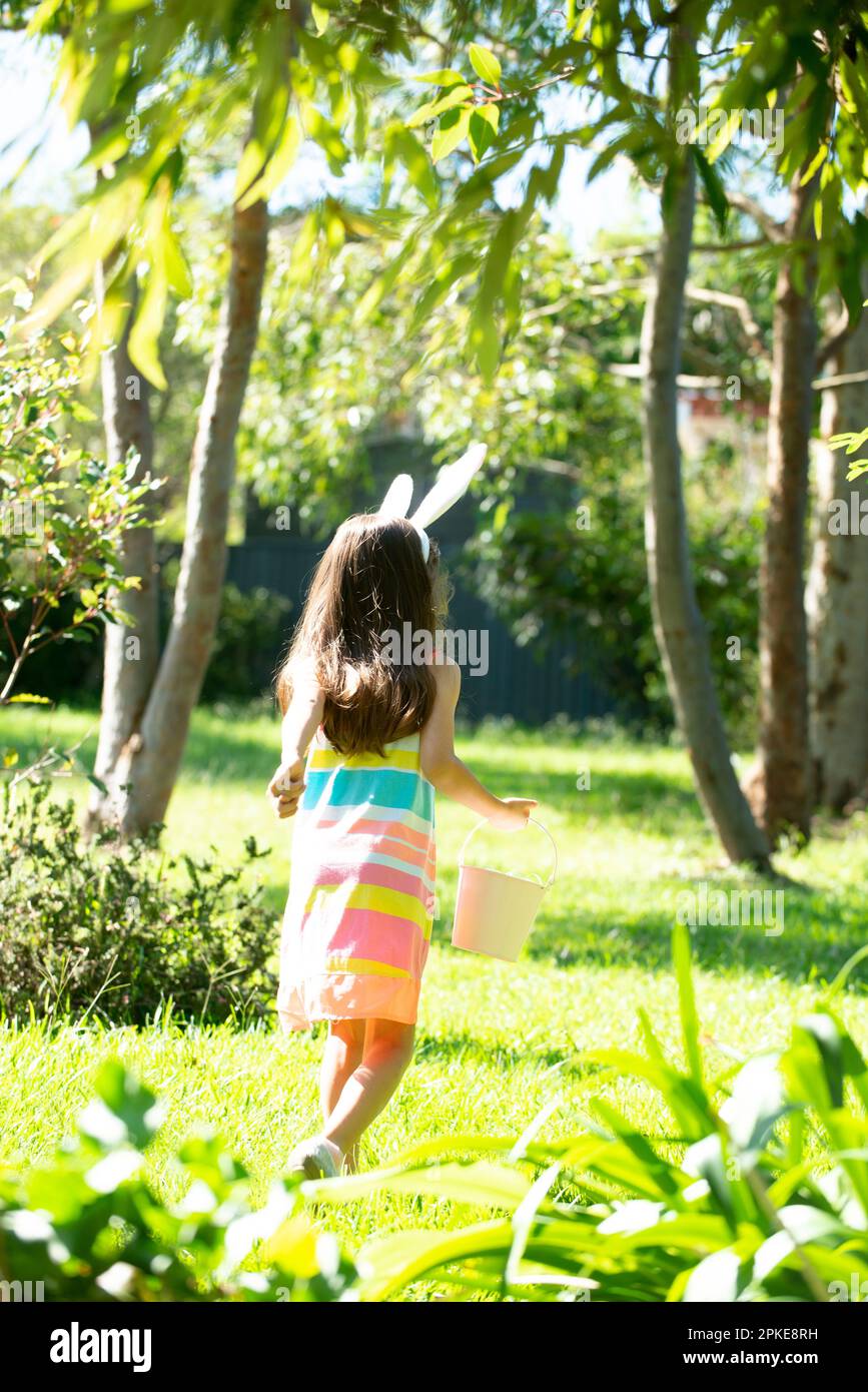 Back view of girl doing Easter egg hunt Stock Photo - Alamy
