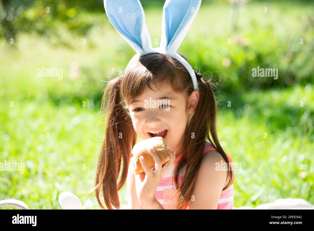 Girl eating Easter hot cross bun Stock Photo - Alamy