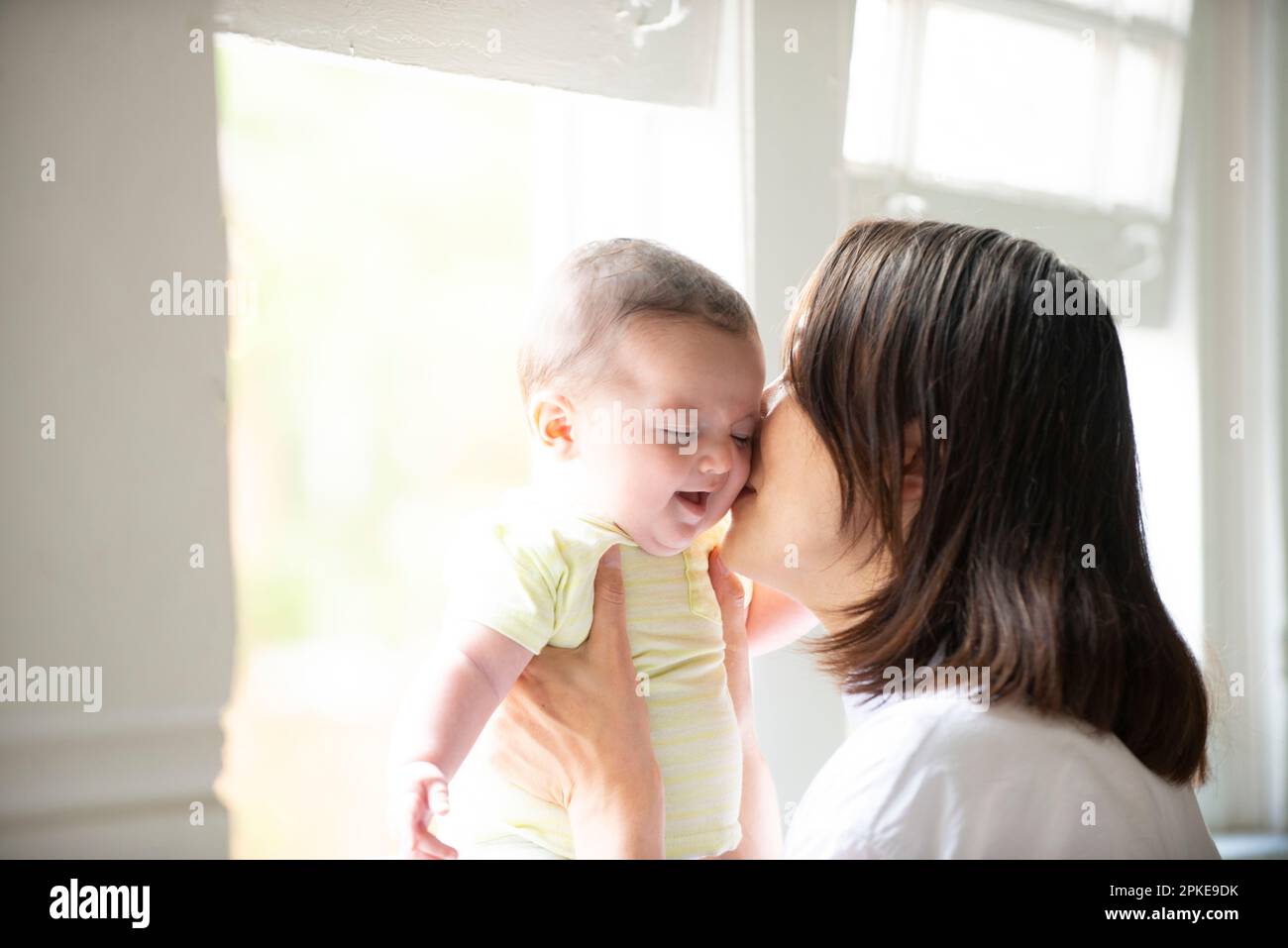 Mother kissing baby at window Stock Photo - Alamy