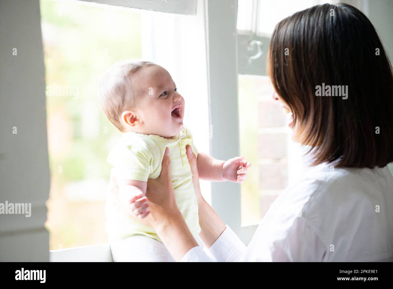 Mother nursing baby by window Stock Photo - Alamy