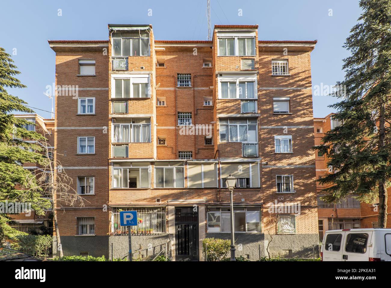 Facade of a cheap brick clay building with street trees and gardens ...