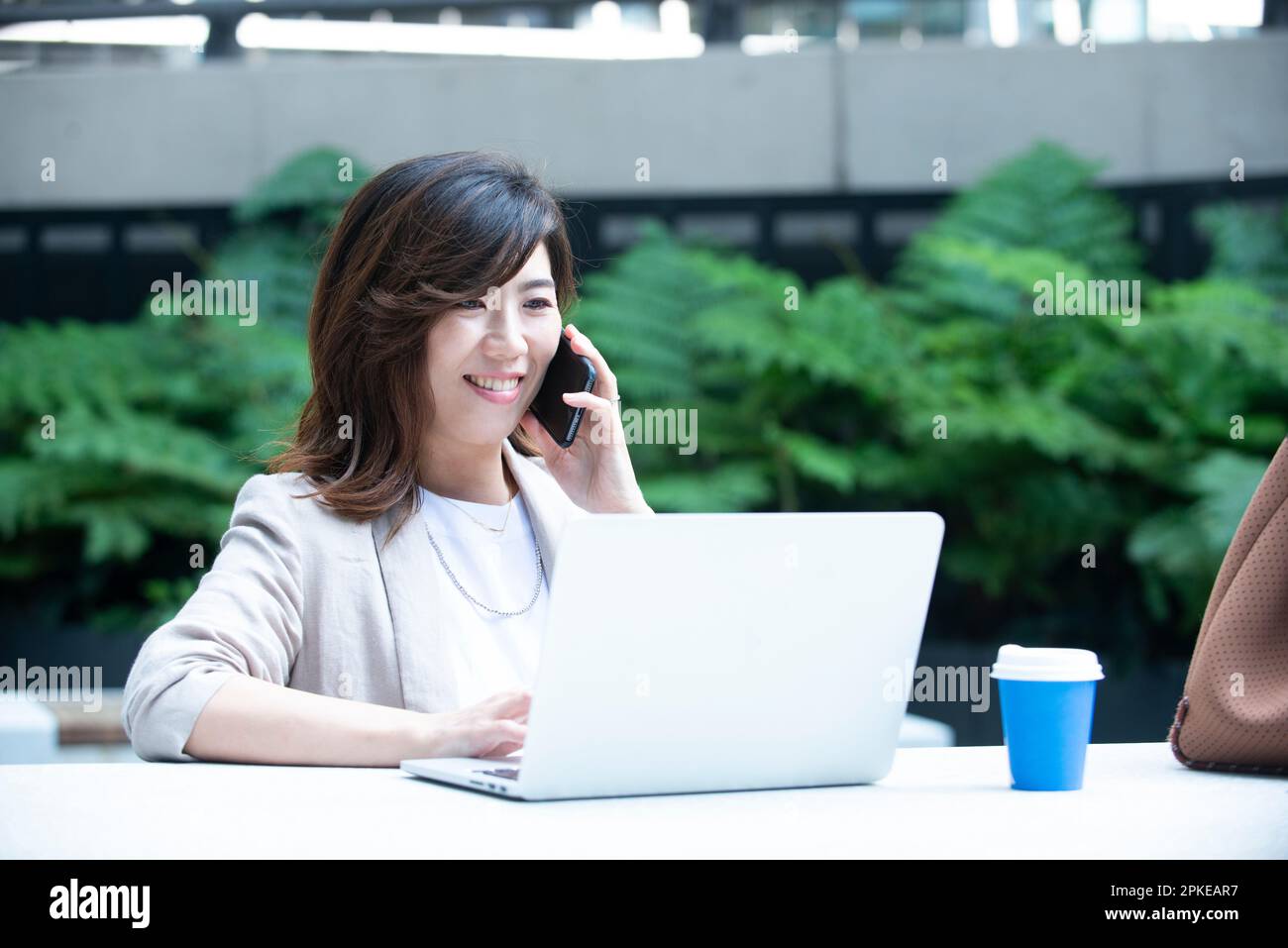 Woman on the phone with computer open outside Stock Photo - Alamy
