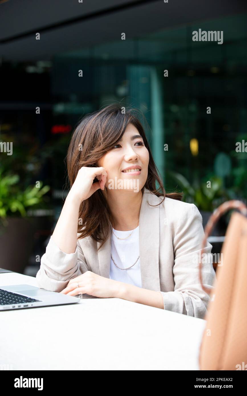 Woman with computer open outside looking into the distance Stock Photo ...